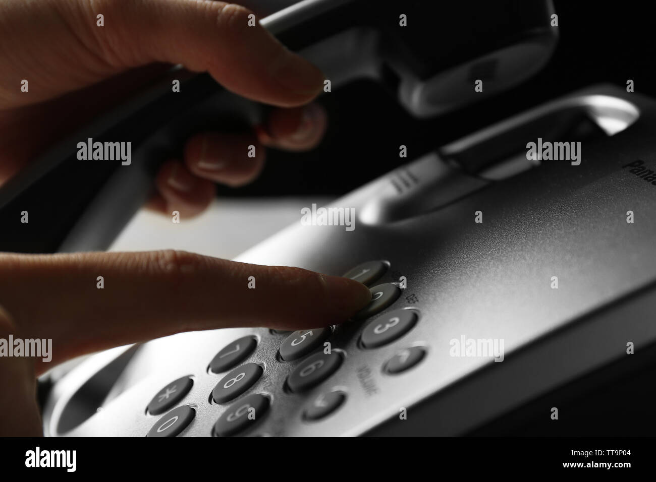 Finger pressing number button on telephone to make a call, close up ...