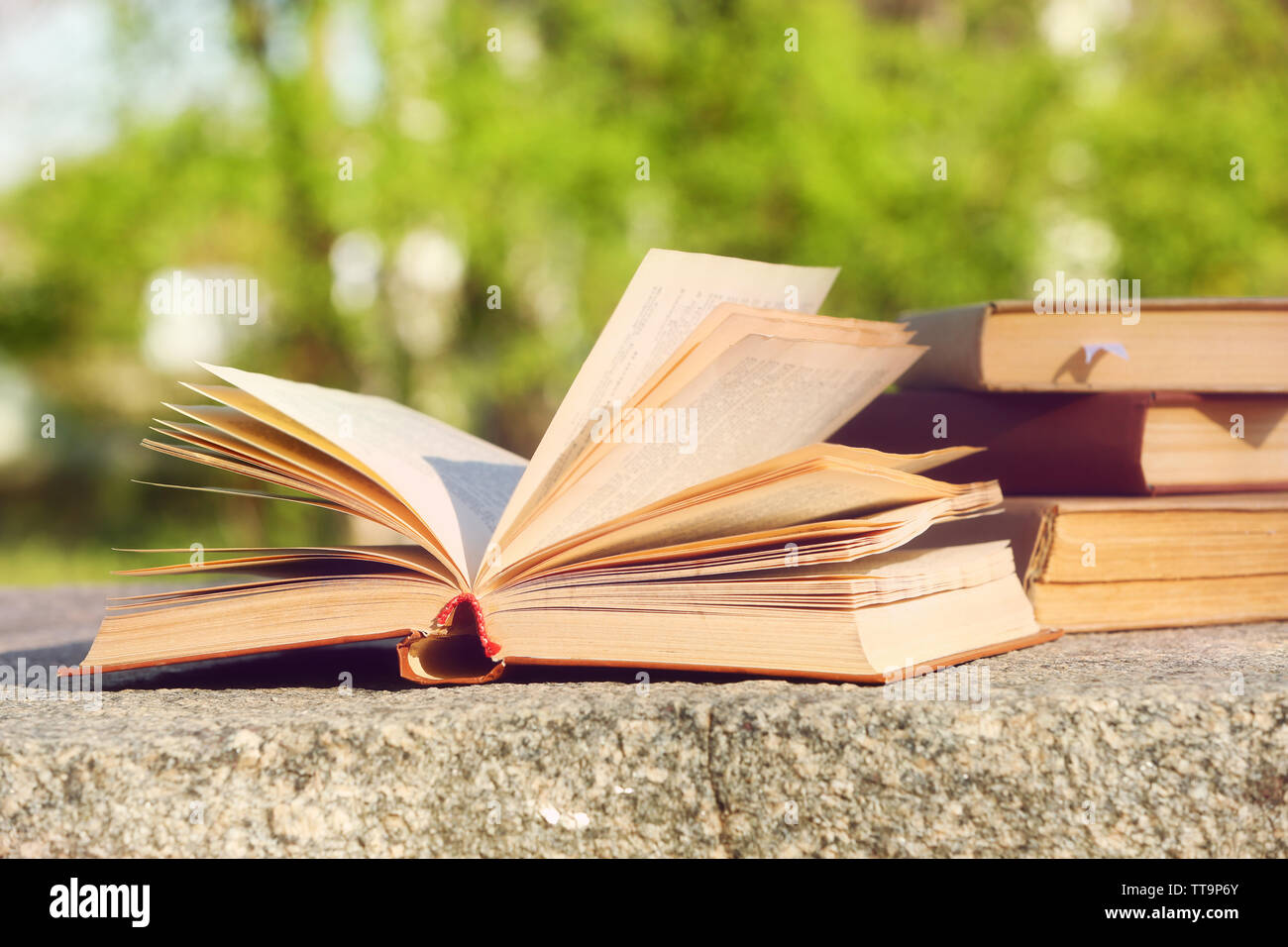 Stack of books outdoors, on blurred background Stock Photo - Alamy