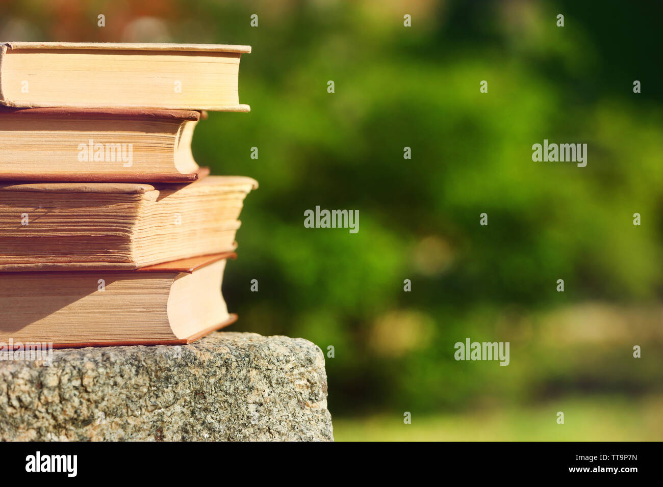 Stack of books outdoors, on blurred background Stock Photo - Alamy