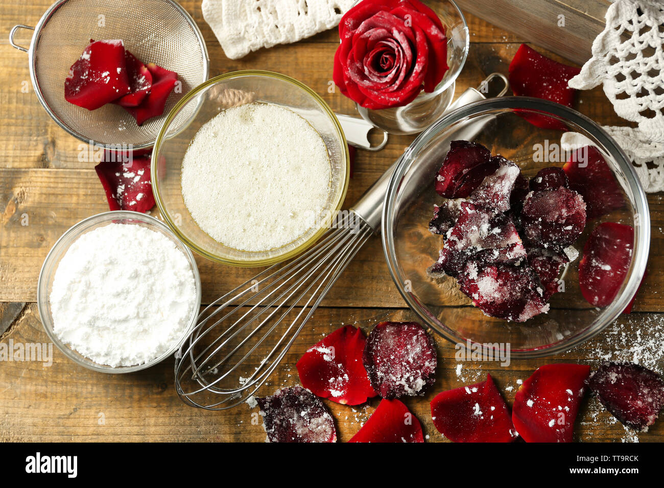 Making candied rose flower petals with egg whites and sugar, on wooden ...