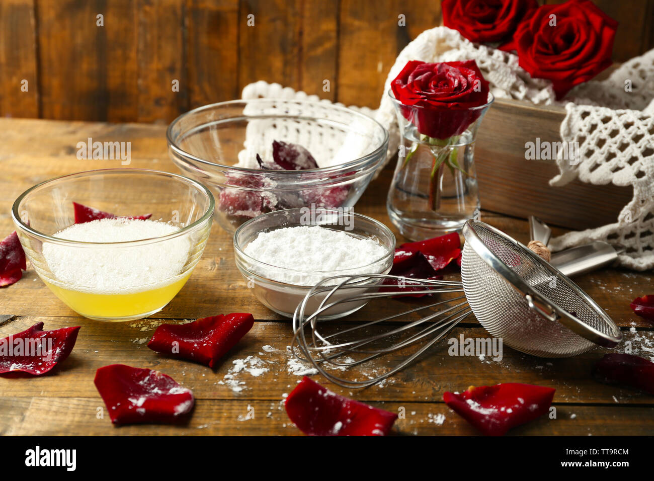 Making candied rose flower petals with egg whites and sugar, on wooden ...