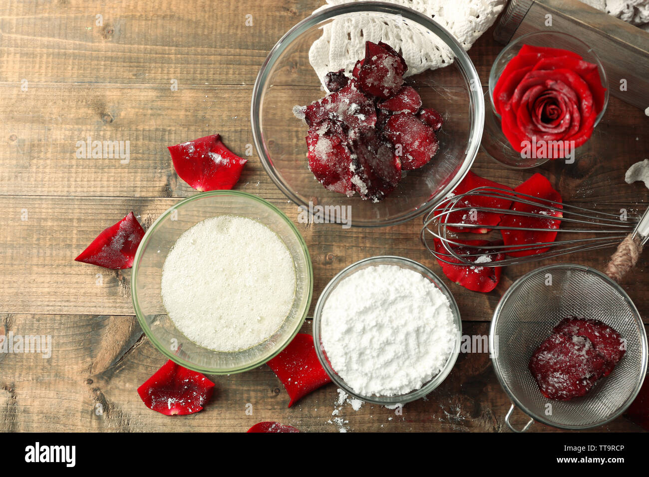 Making candied rose flower petals with egg whites and sugar, on wooden ...