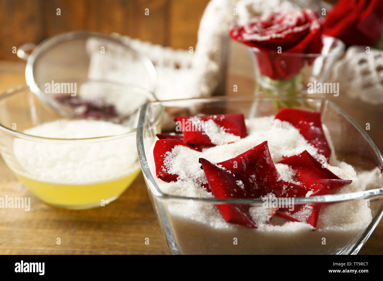 Making candied rose flower petals with egg whites and sugar, on wooden ...