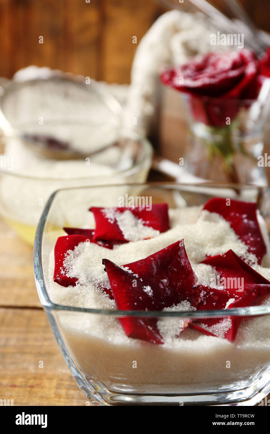 Making candied rose flower petals with egg whites and sugar, on wooden ...
