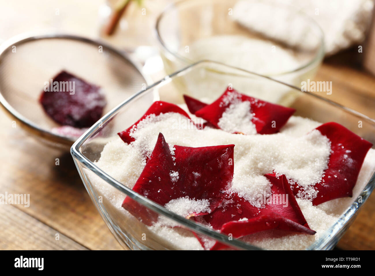 Making candied rose flower petals with egg whites and sugar, on wooden ...