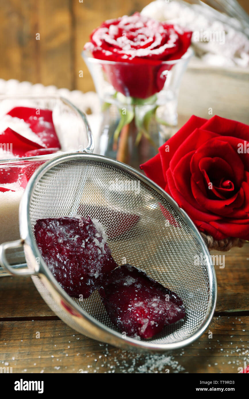 Making candied rose flower petals with egg whites and sugar, on wooden ...
