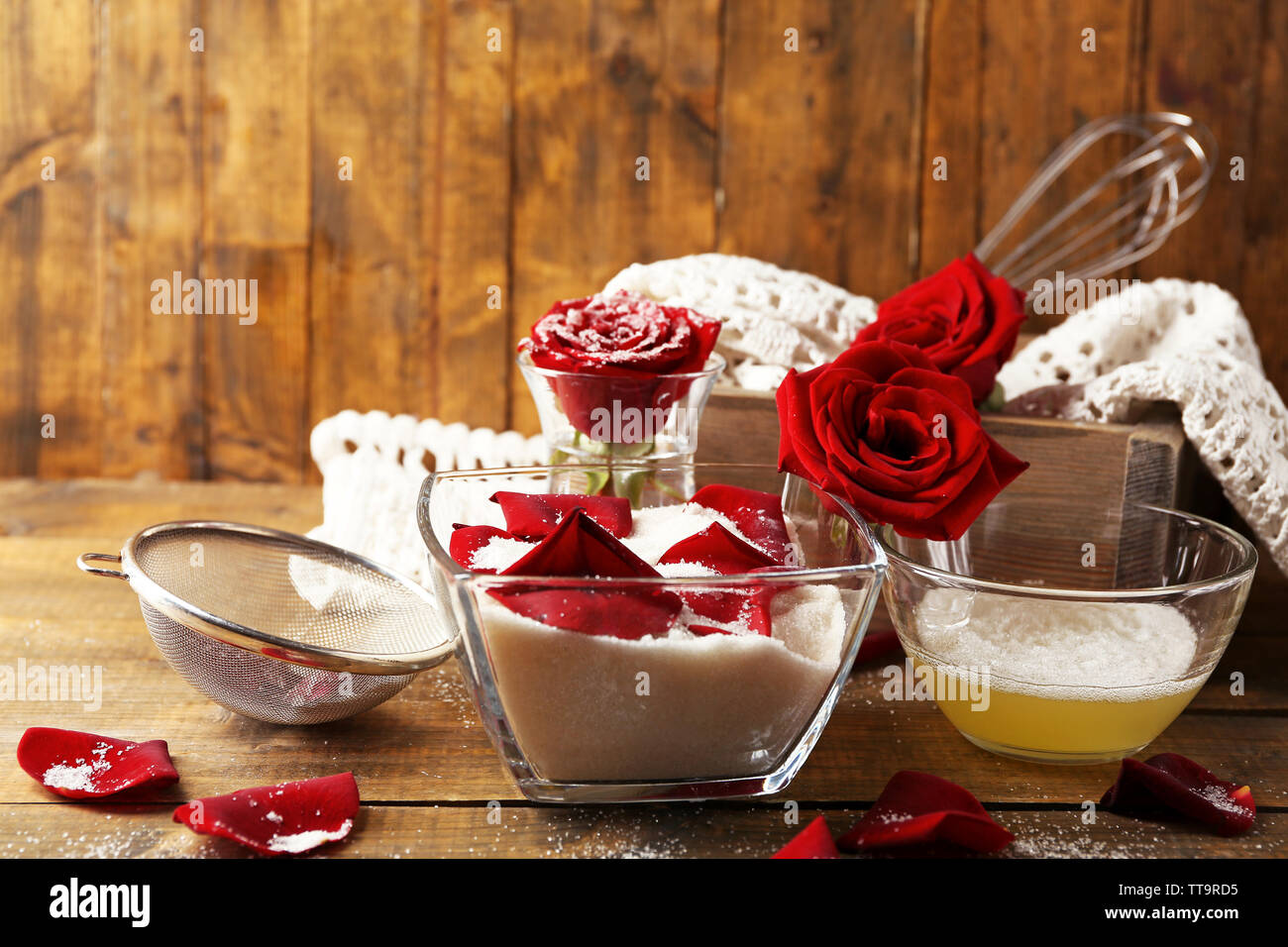 Making candied rose flower petals with egg whites and sugar, on wooden ...