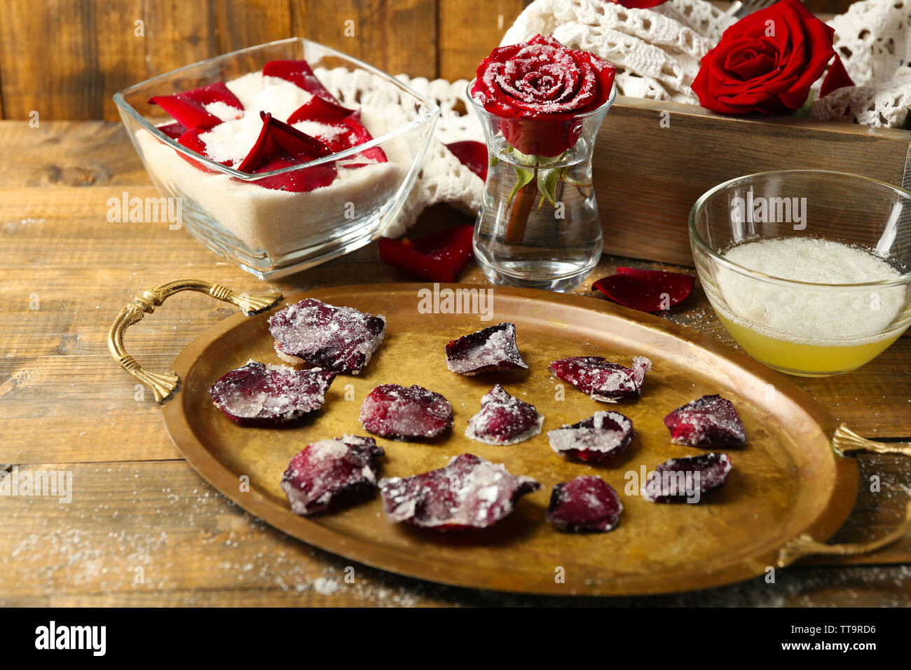Making candied rose flower petals with egg whites and sugar, on wooden ...