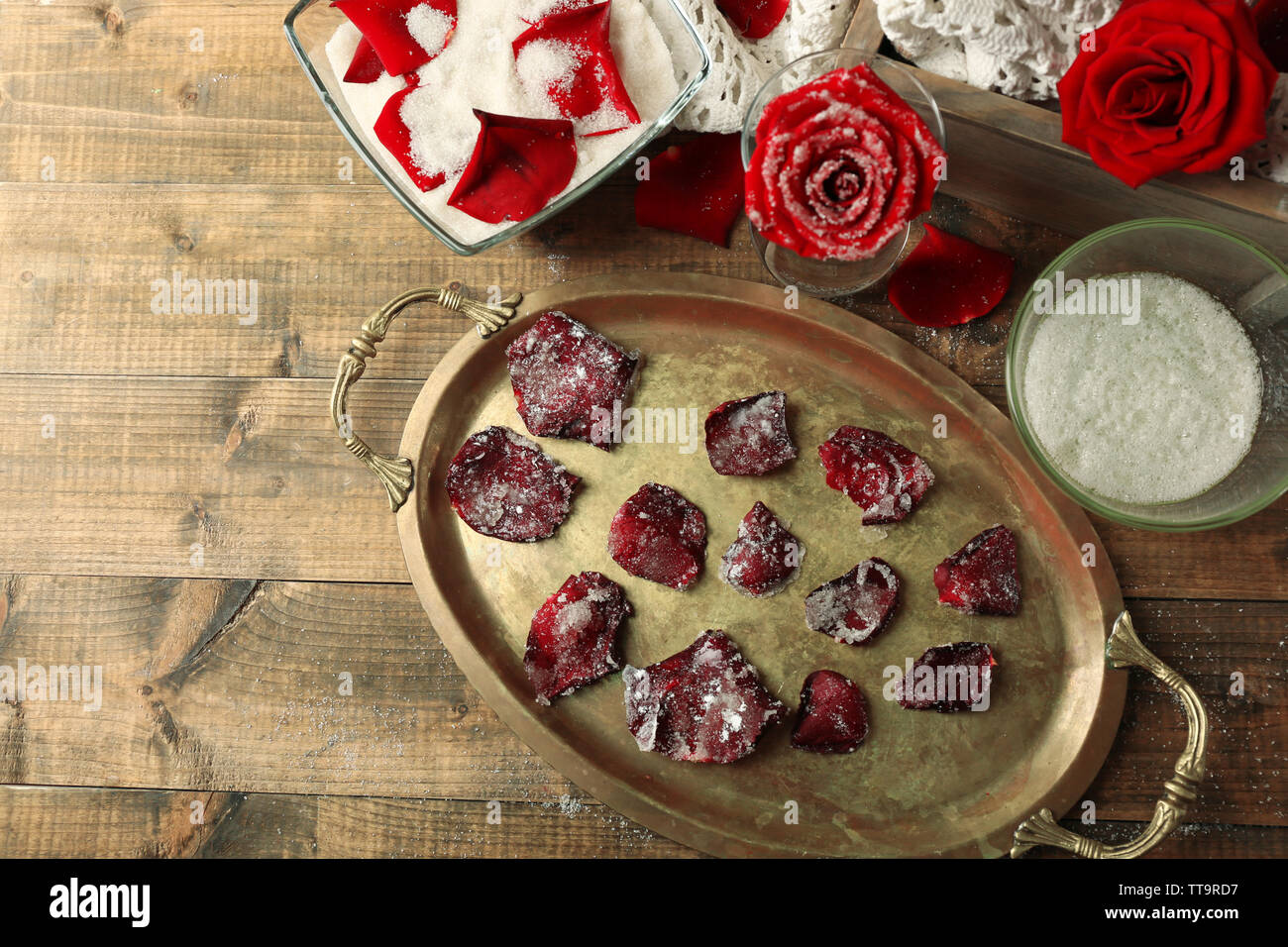 Making candied rose flower petals with egg whites and sugar, on wooden ...