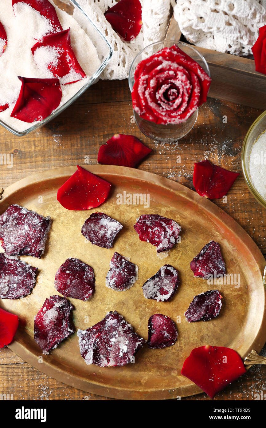 Making candied rose flower petals with egg whites and sugar, on wooden ...