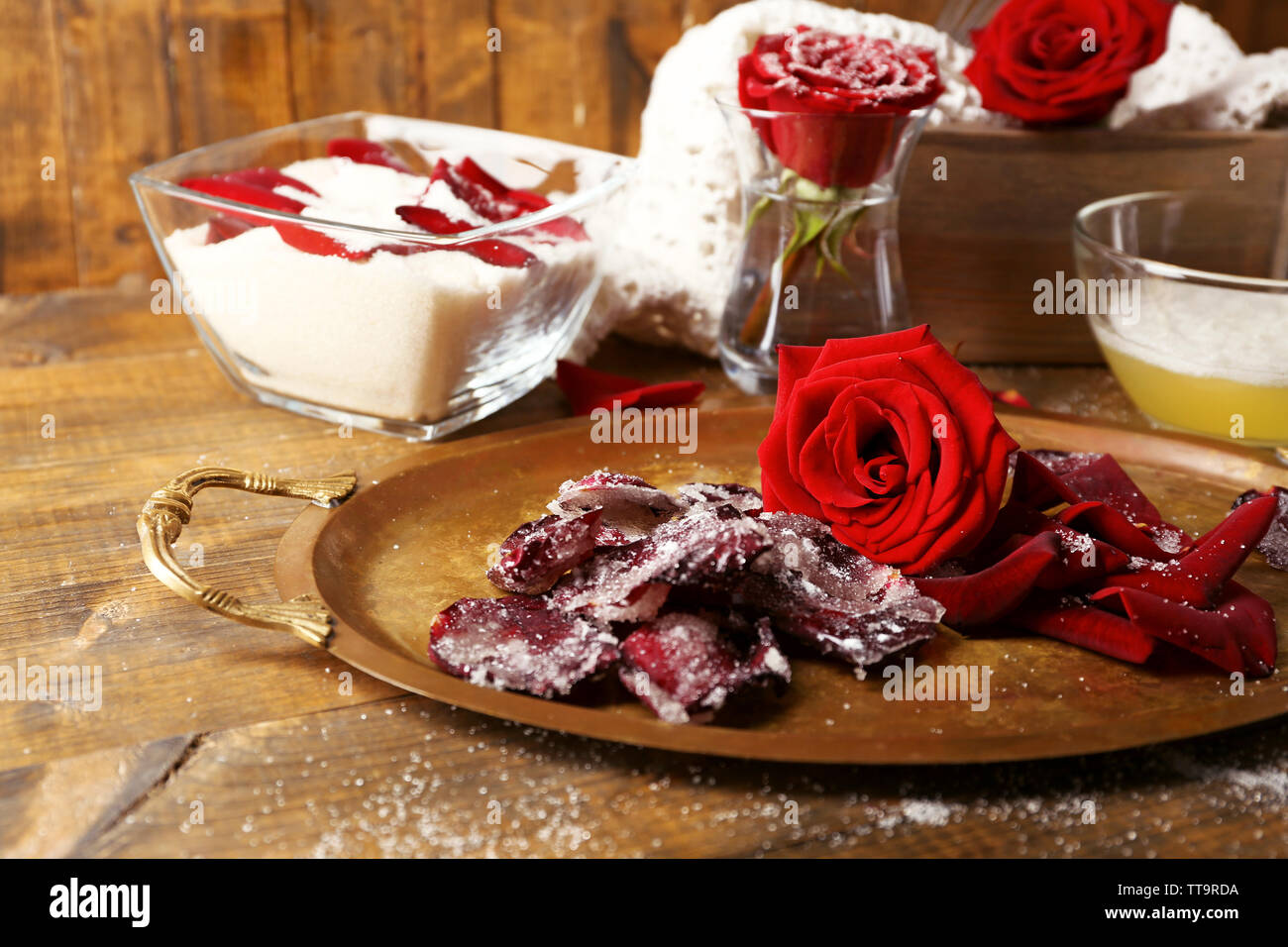 Making candied rose flower petals with egg whites and sugar, on wooden ...