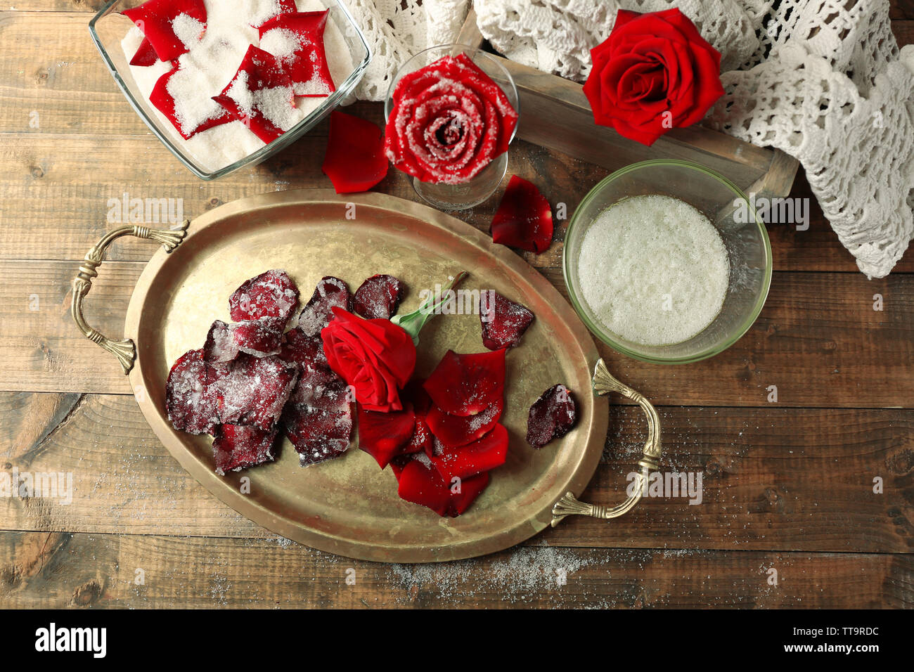 Making candied rose flower petals with egg whites and sugar, on wooden ...