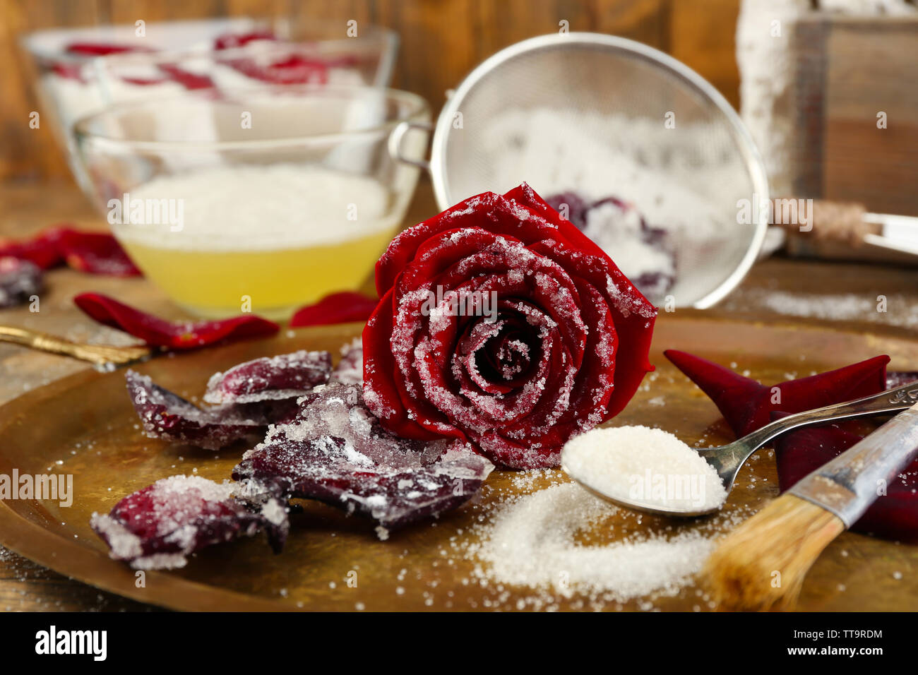Making candied rose flower petals with egg whites and sugar, on wooden ...