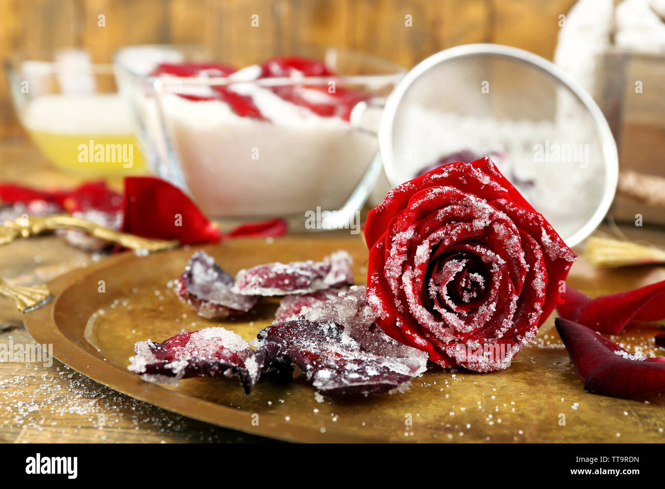 Making candied rose flower petals with egg whites and sugar, on wooden ...