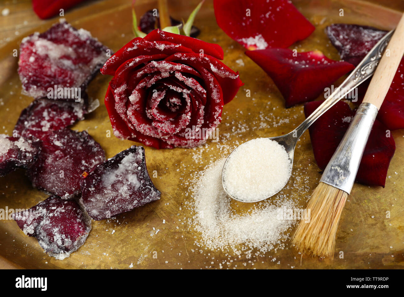 Making candied rose flower petals with egg whites and sugar, on wooden ...