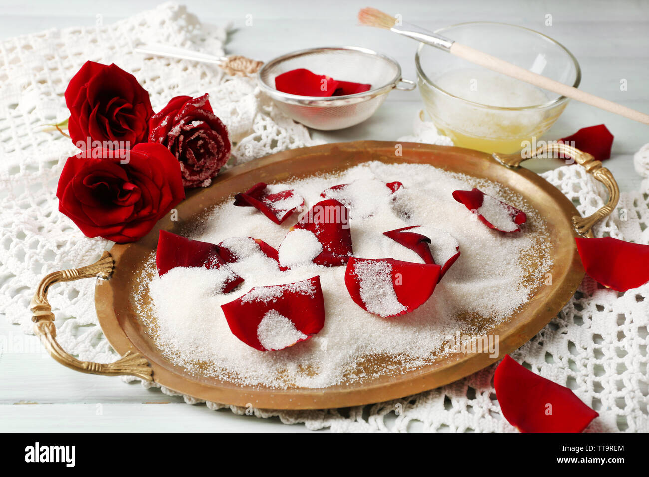 Making candied rose flower petals with egg whites and sugar, on wooden ...