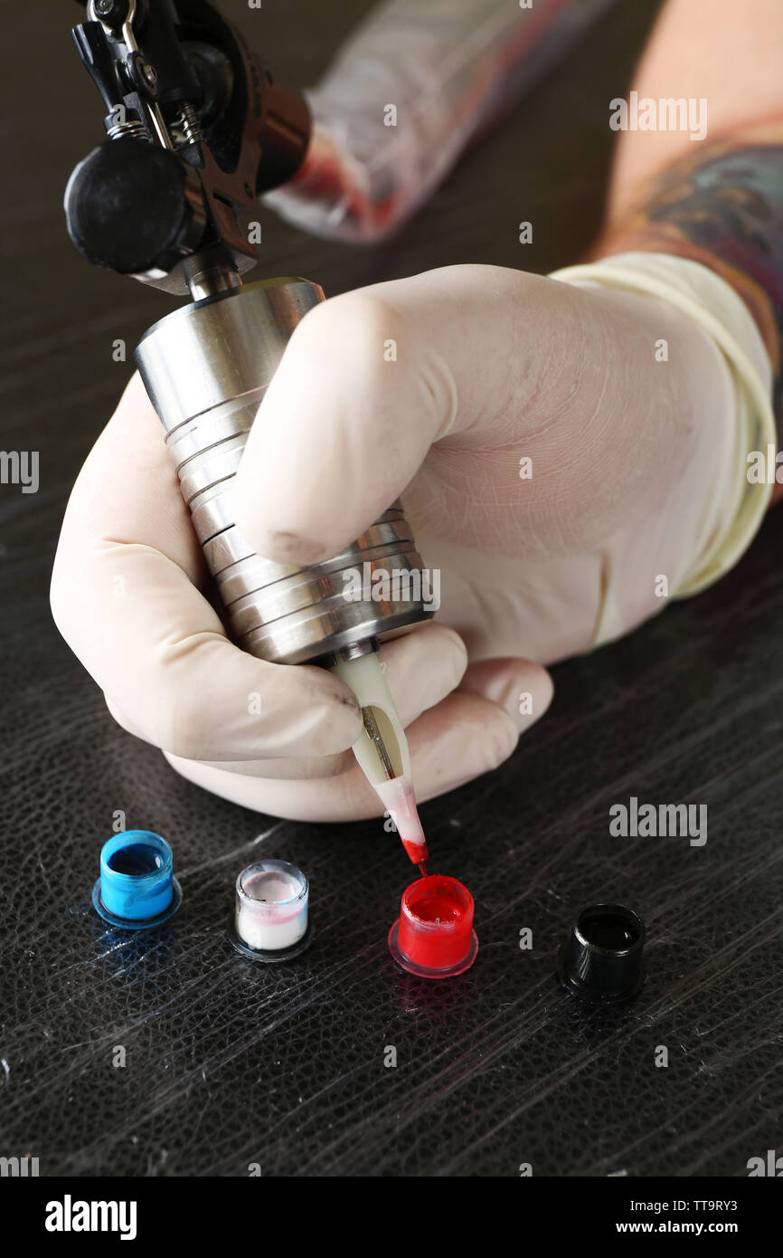 Tattoo artist at work close up Stock Photo - Alamy