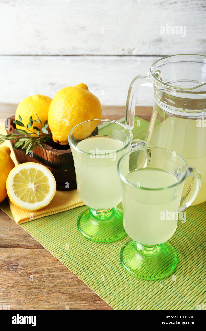 Still life with lemon juice and sliced lemons on wooden background ...