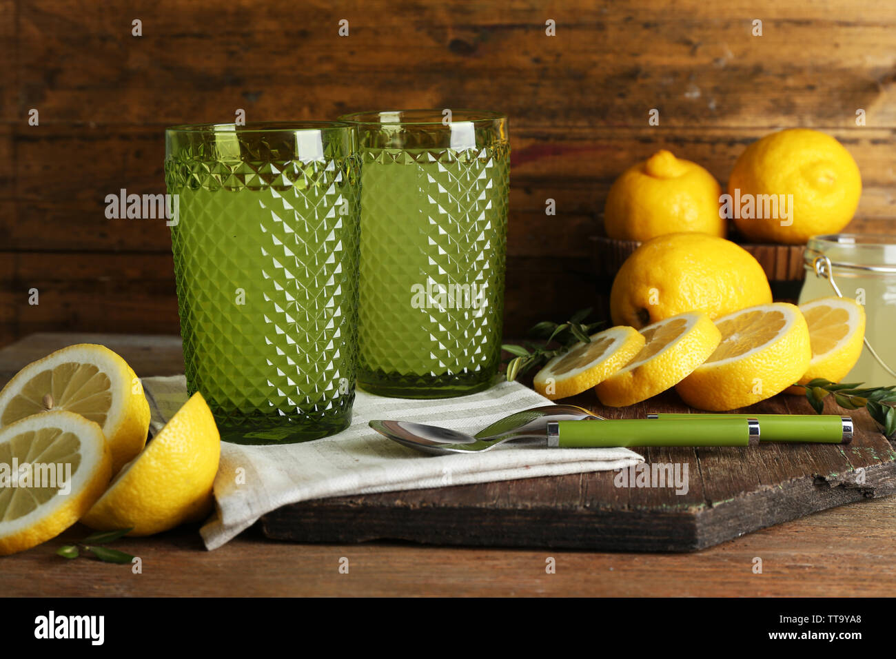Still life with lemon juice and sliced lemons on wooden background ...