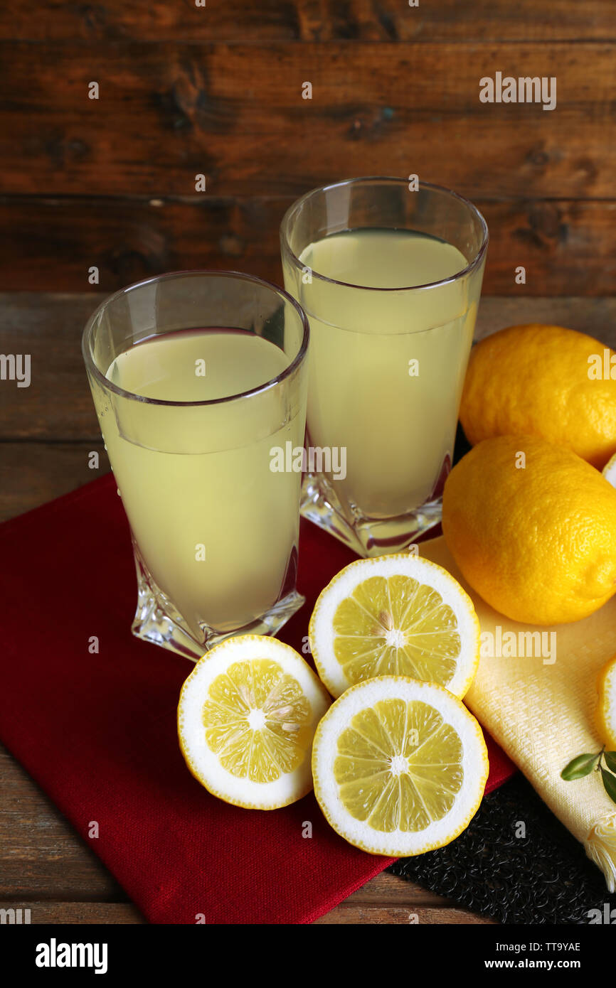 Still life with lemon juice and sliced lemons on wooden background ...