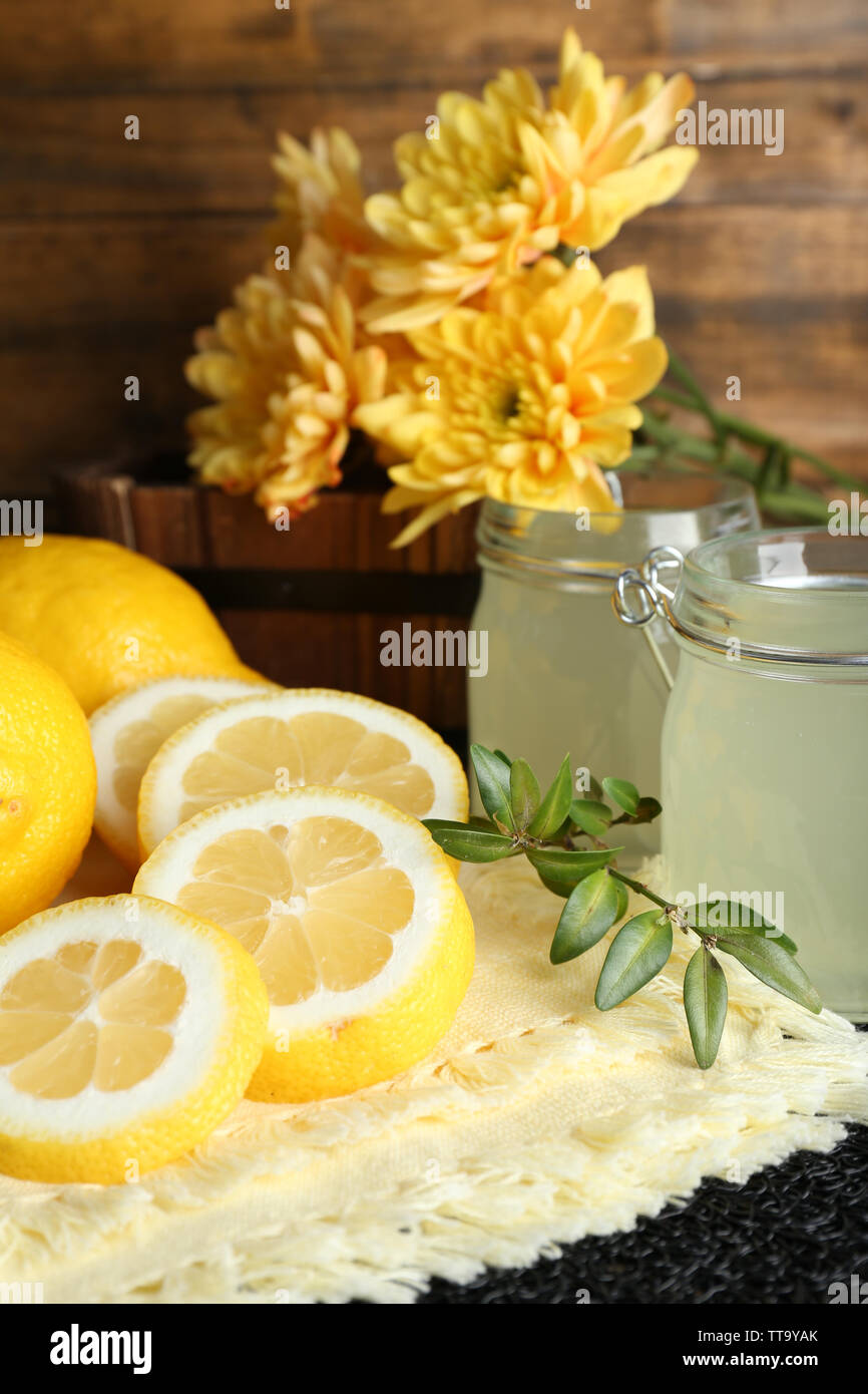 Still life with lemon juice and sliced lemons on wooden background ...