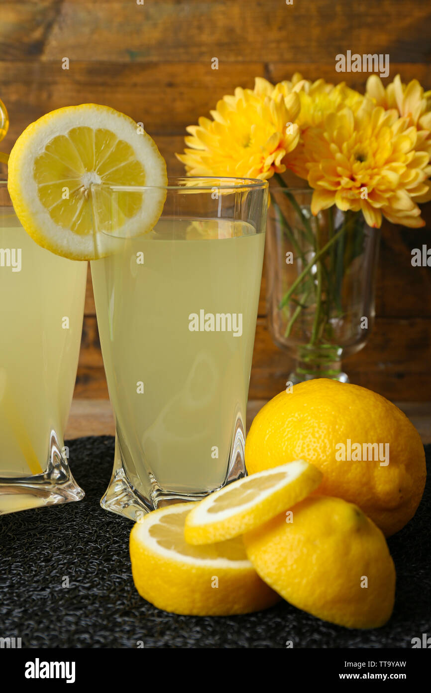 Still life with lemon juice and sliced lemons on wooden background ...