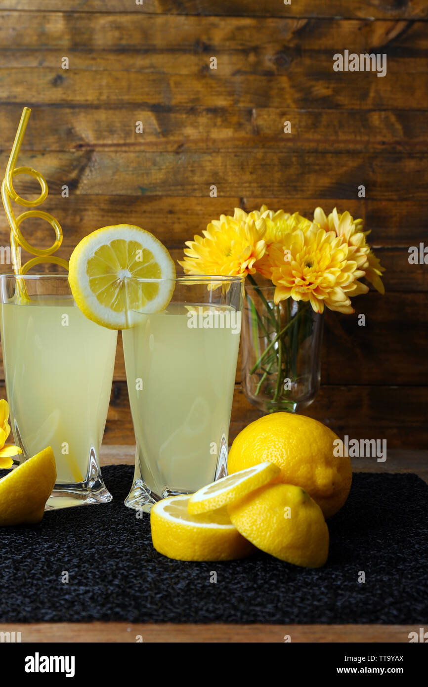 Still life with lemon juice and sliced lemons on wooden background ...