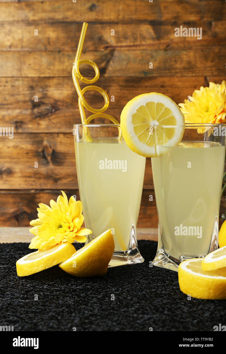Still life with lemon juice and sliced lemons on wooden background ...