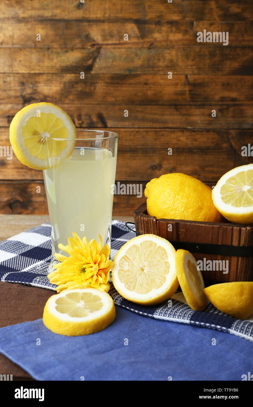 Still life with lemon juice and sliced lemons on wooden background ...