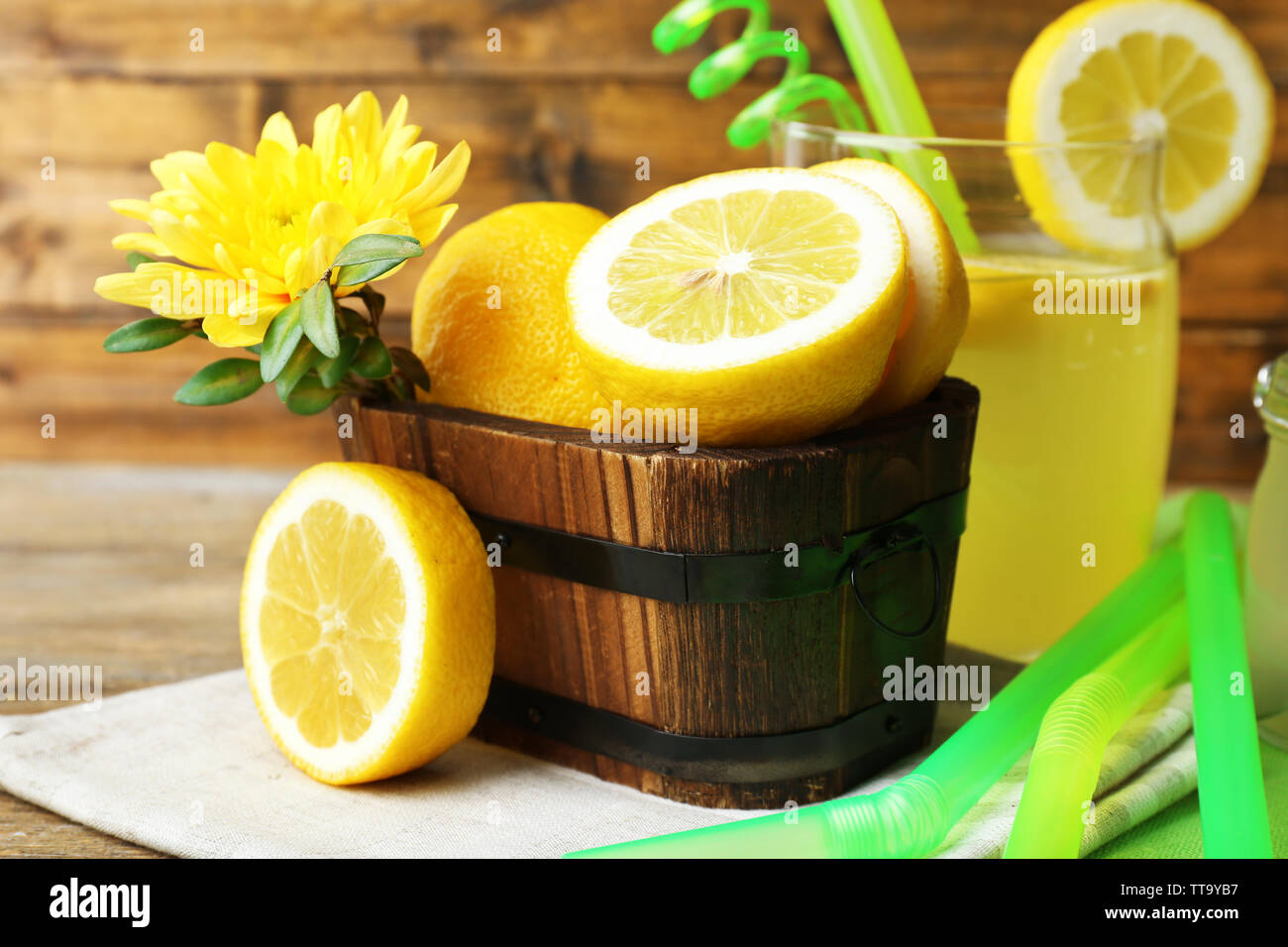 Still life with lemon juice and sliced lemons on wooden background ...