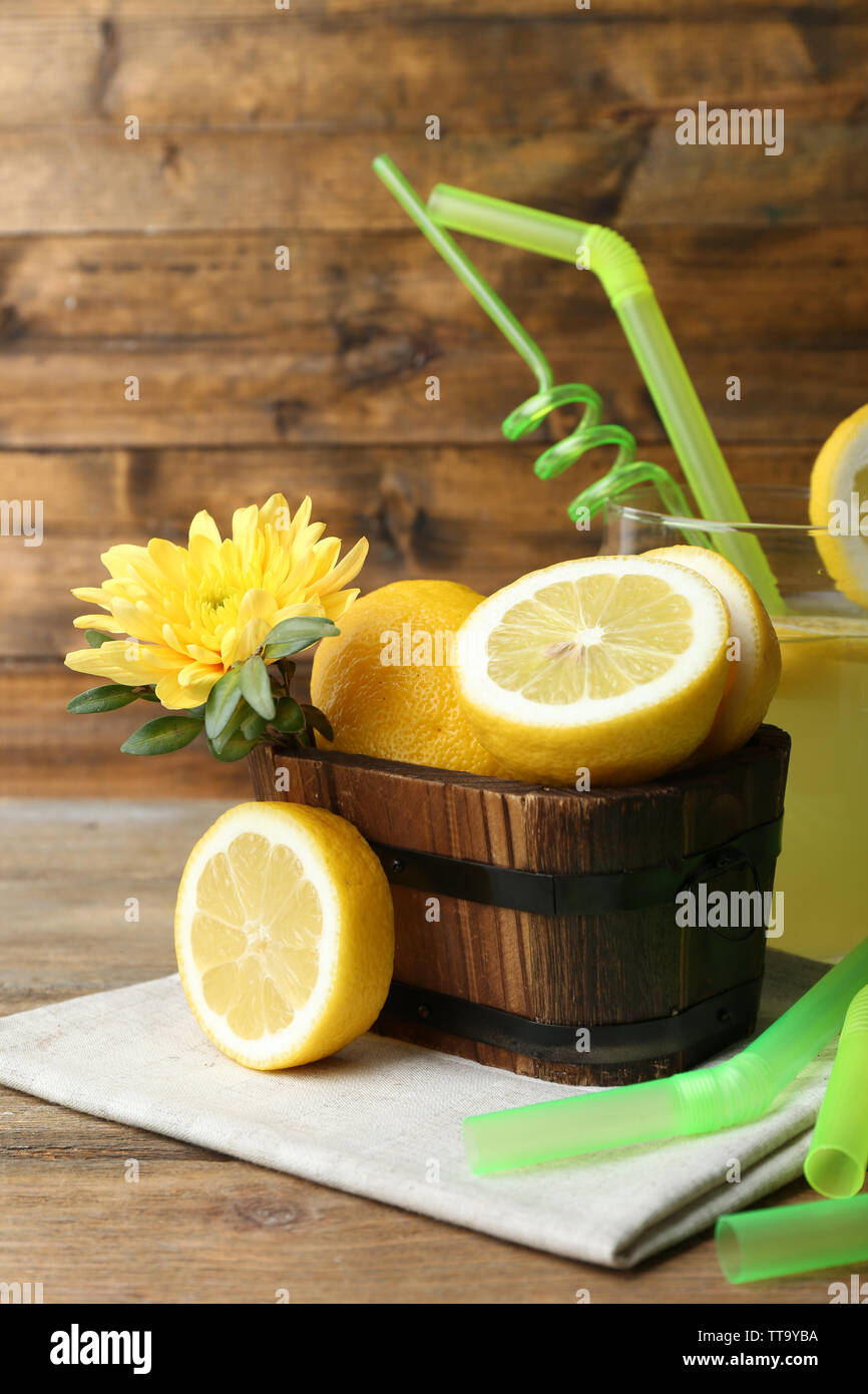Still life with lemon juice and sliced lemons on wooden background ...