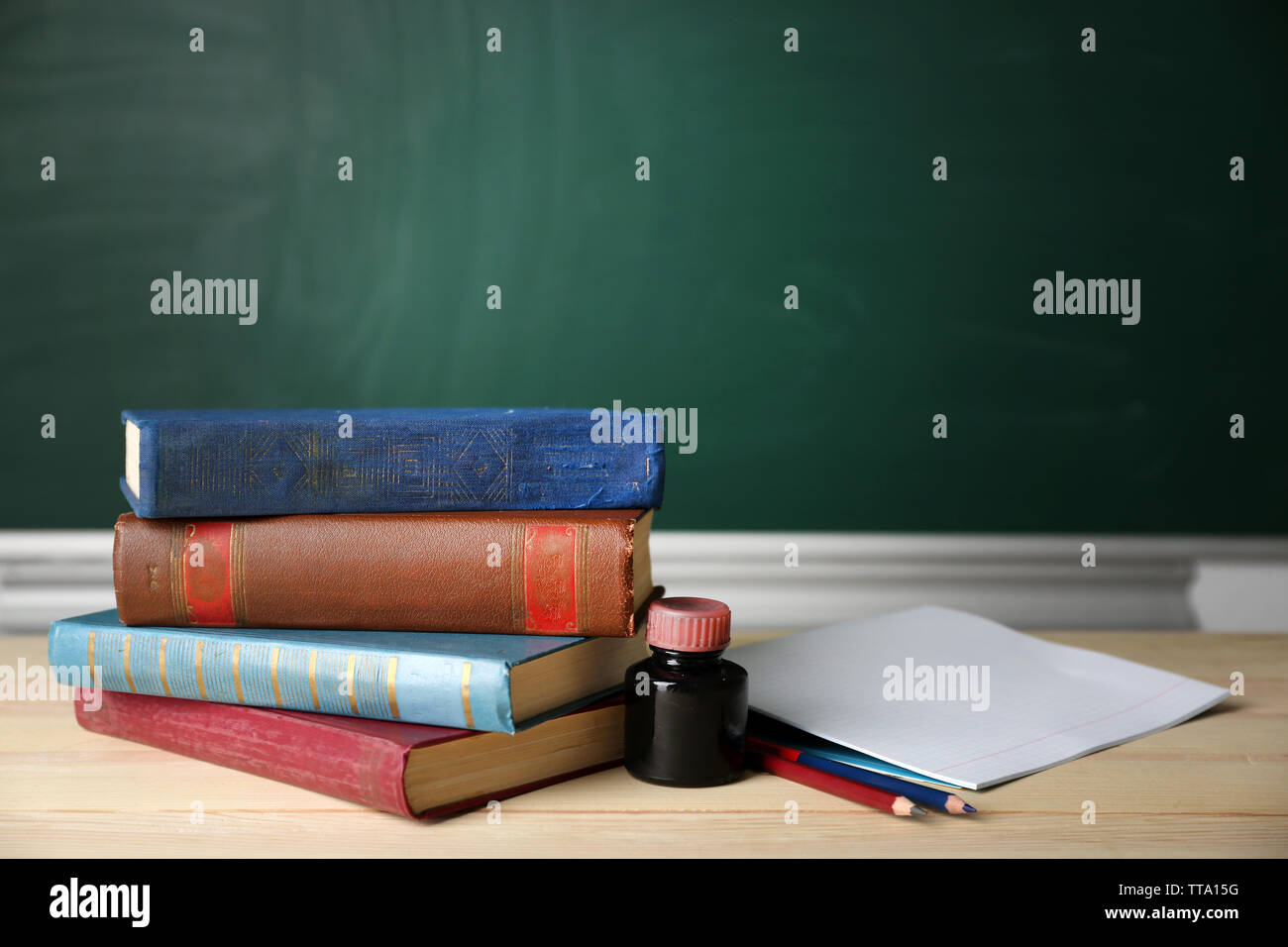 Stack of books on desk, on blackboard background Stock Photo - Alamy