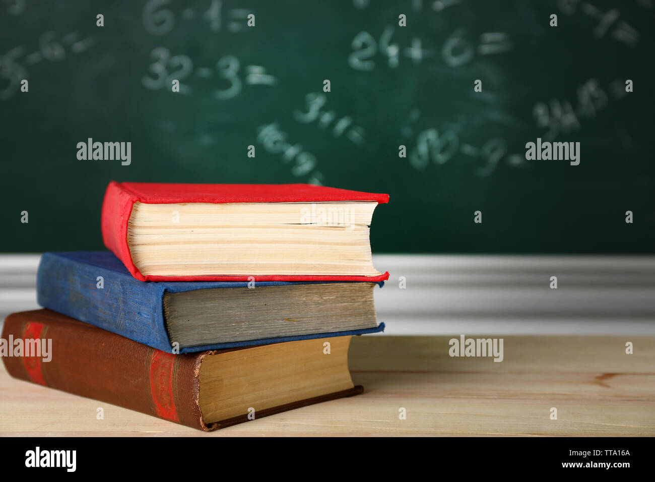 Stack of books on desk, on blackboard background Stock Photo - Alamy