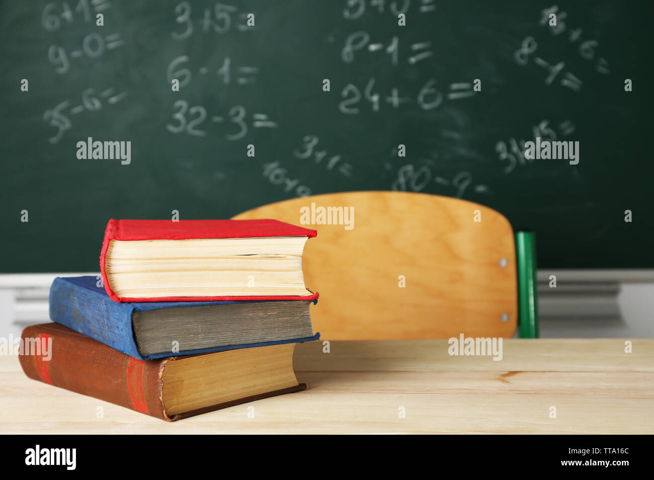 Stack of books on desk, on blackboard background Stock Photo - Alamy