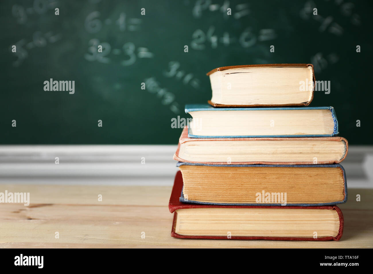 Stack of books on desk, on blackboard background Stock Photo - Alamy