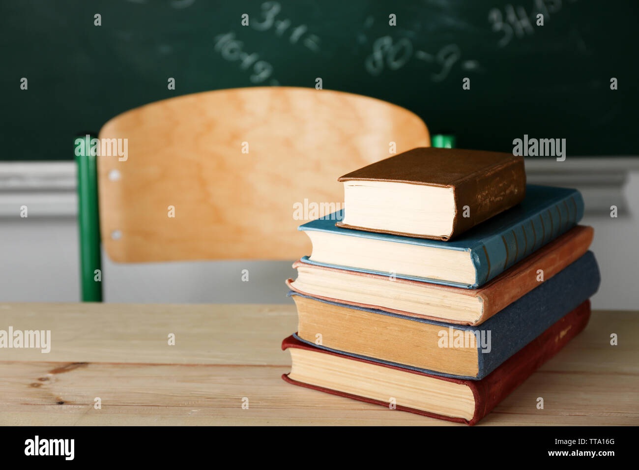 Stack of books on desk, on blackboard background Stock Photo - Alamy
