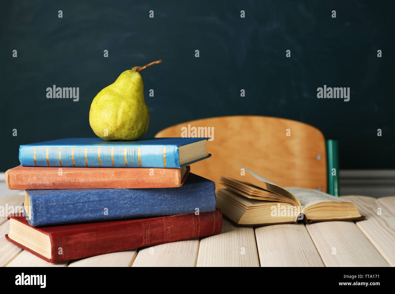 Stack of books on desk, on blackboard background Stock Photo - Alamy