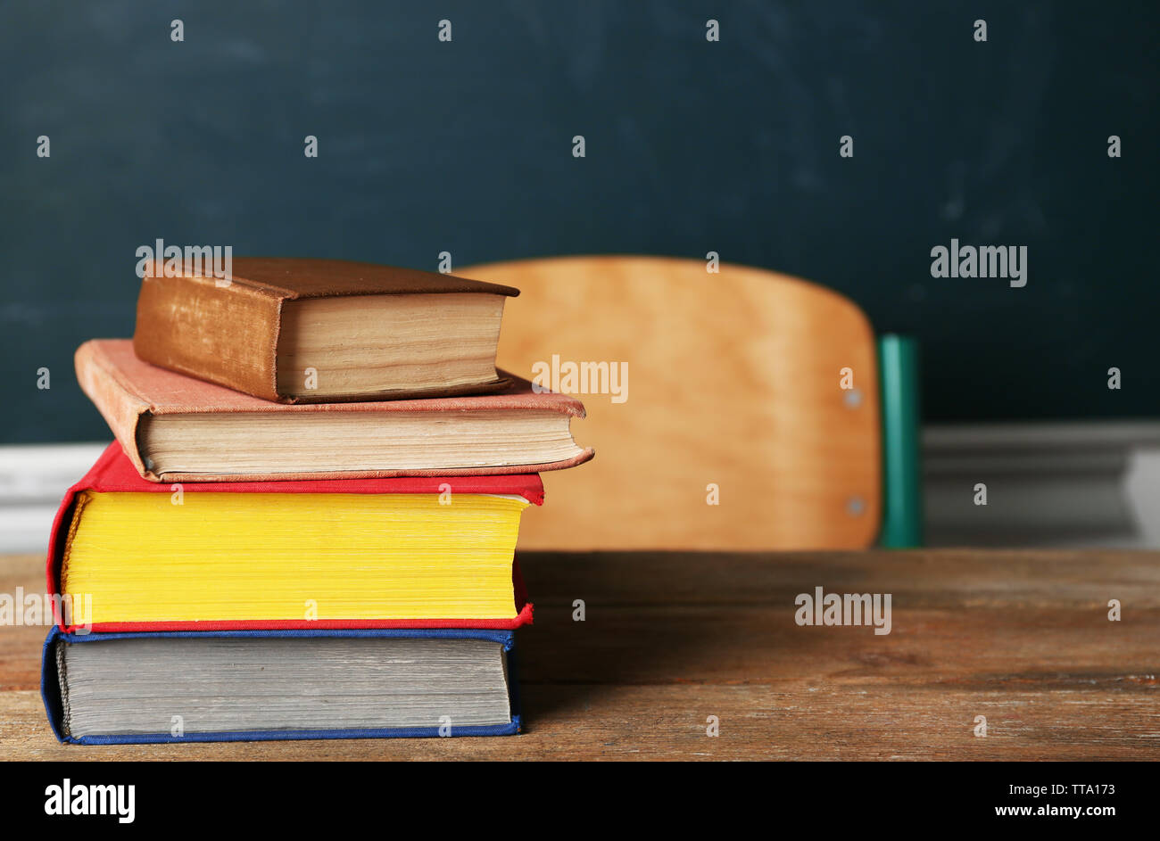 Stack of books on desk, on blackboard background Stock Photo - Alamy