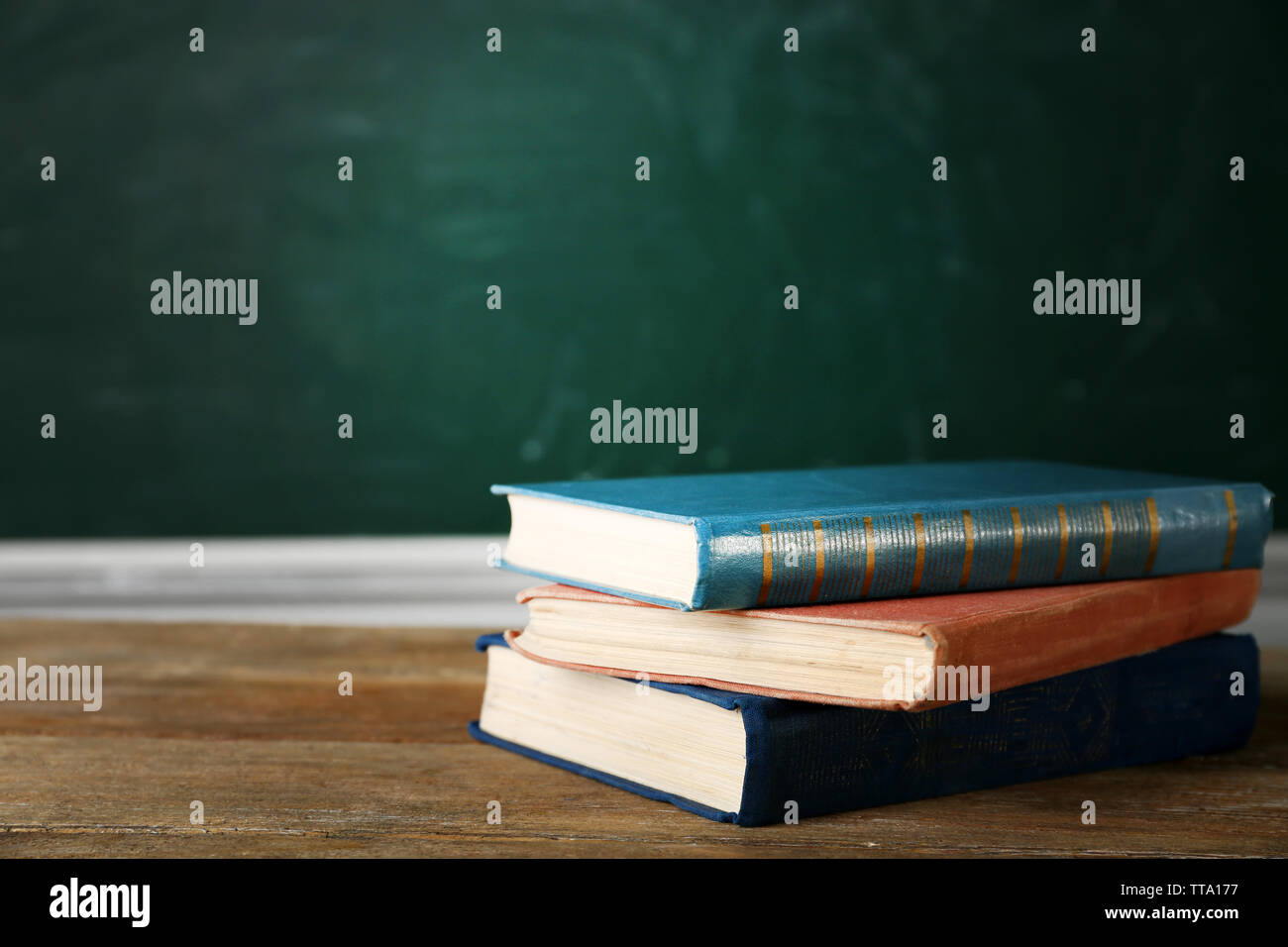 Stack of books on desk, on blackboard background Stock Photo - Alamy