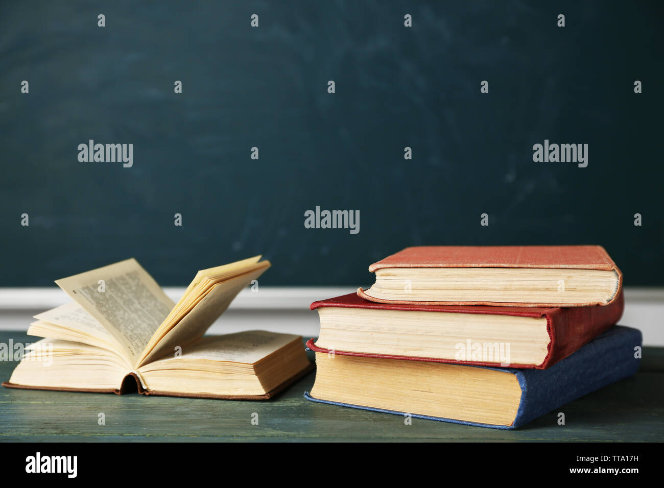 Stack of books on desk, on blackboard background Stock Photo - Alamy