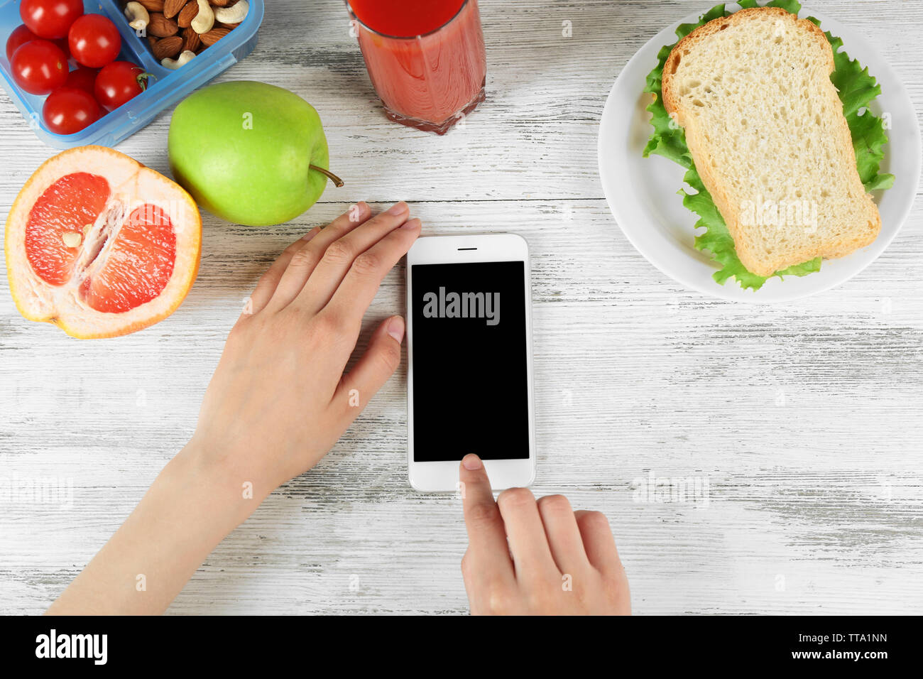 Food and mobile phone in female hands on wooden background Stock Photo ...