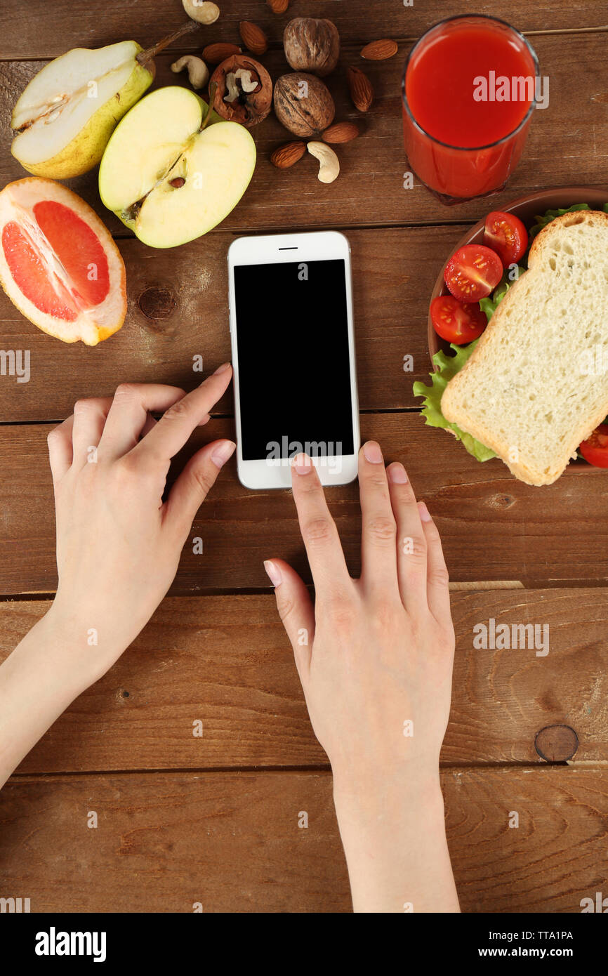 Food and mobile phone in female hands on wooden background Stock Photo ...