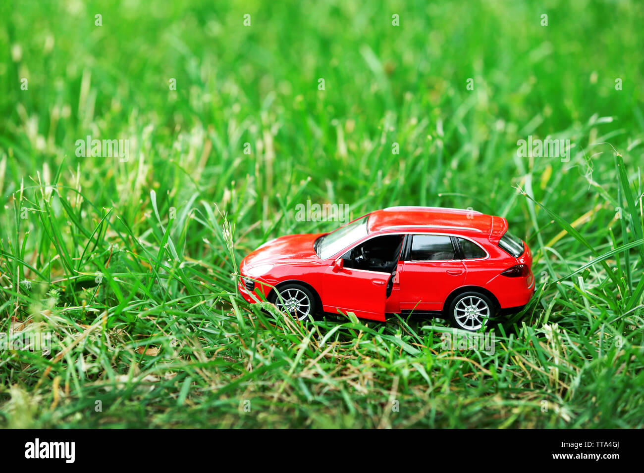 Small car model over green grass background Stock Photo - Alamy