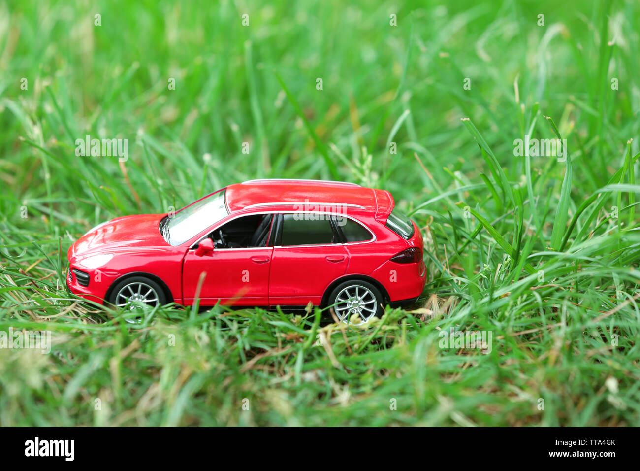Small car model over green grass background Stock Photo - Alamy