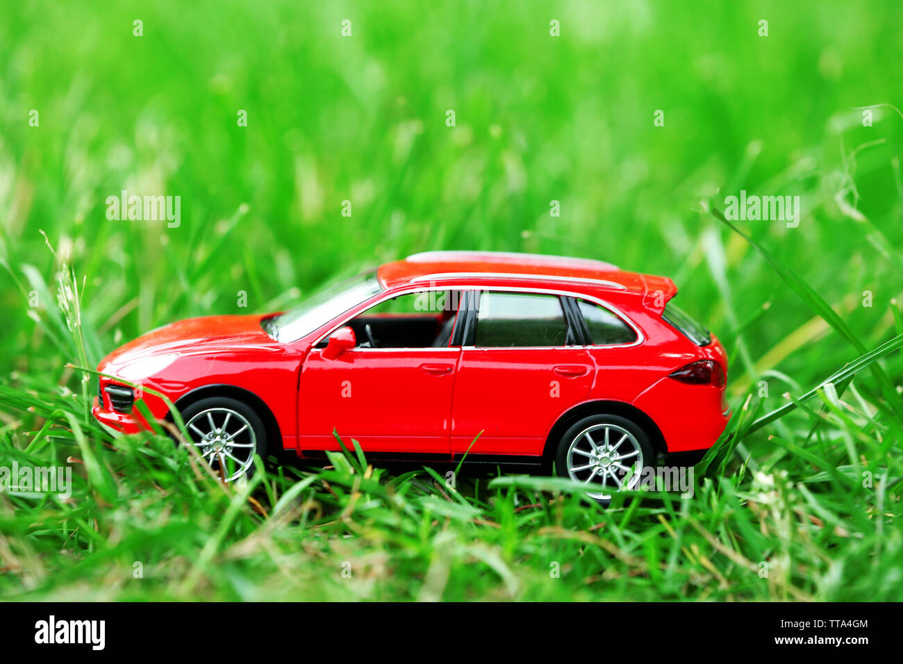 Small car model over green grass background Stock Photo - Alamy