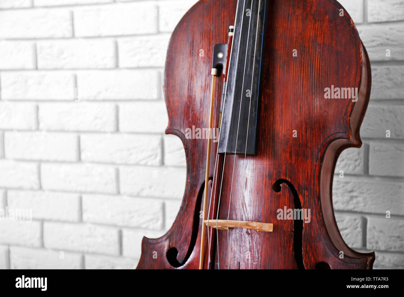 Cello on bricks wall background Stock Photo - Alamy