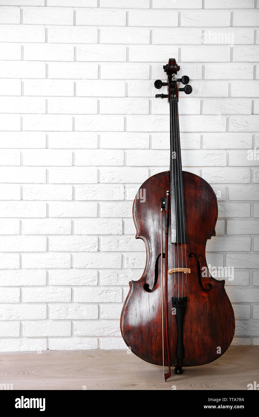 Cello on bricks wall background Stock Photo - Alamy