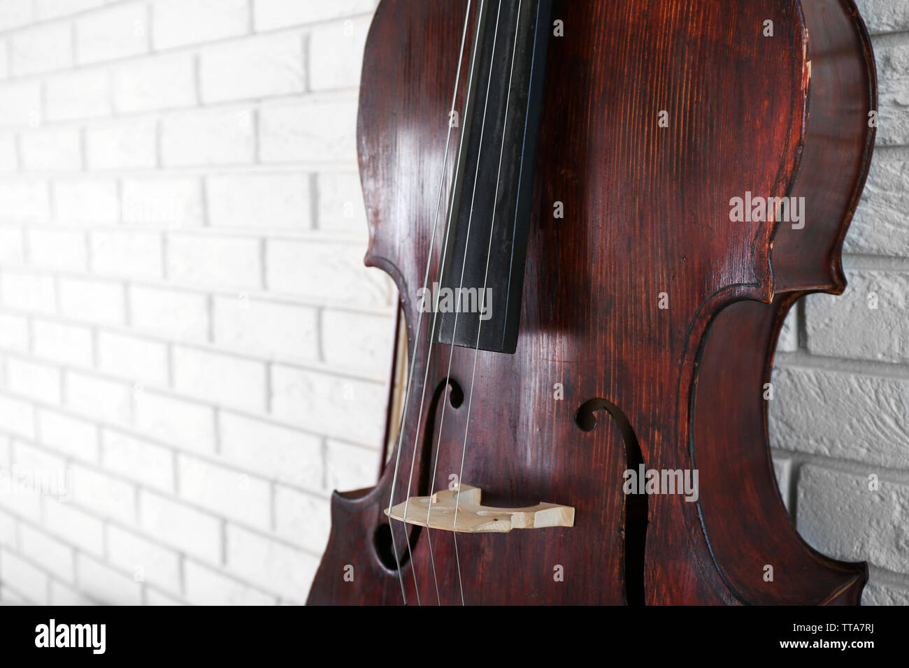 Cello on bricks wall background Stock Photo - Alamy