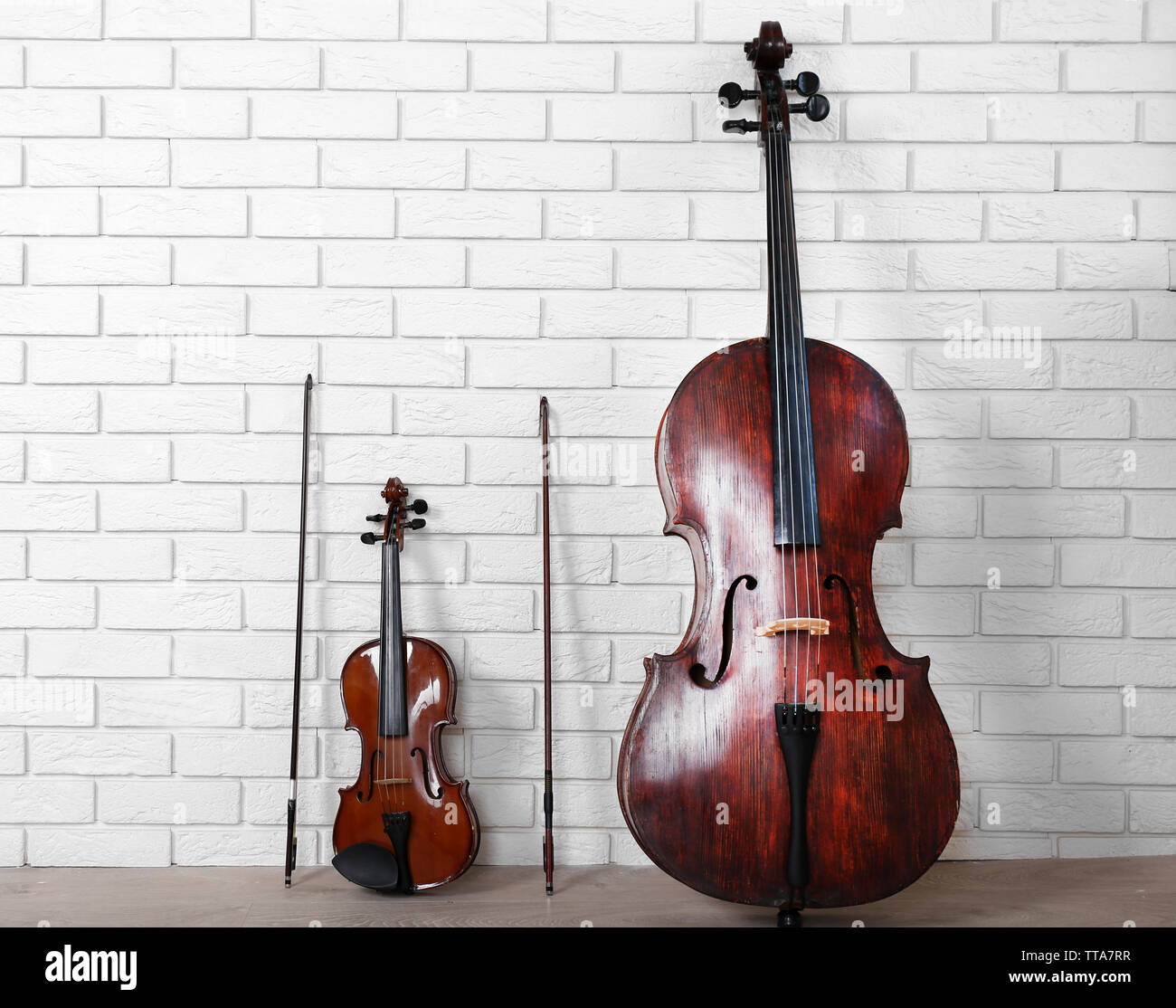 Cello and violin on bricks wall background Stock Photo - Alamy