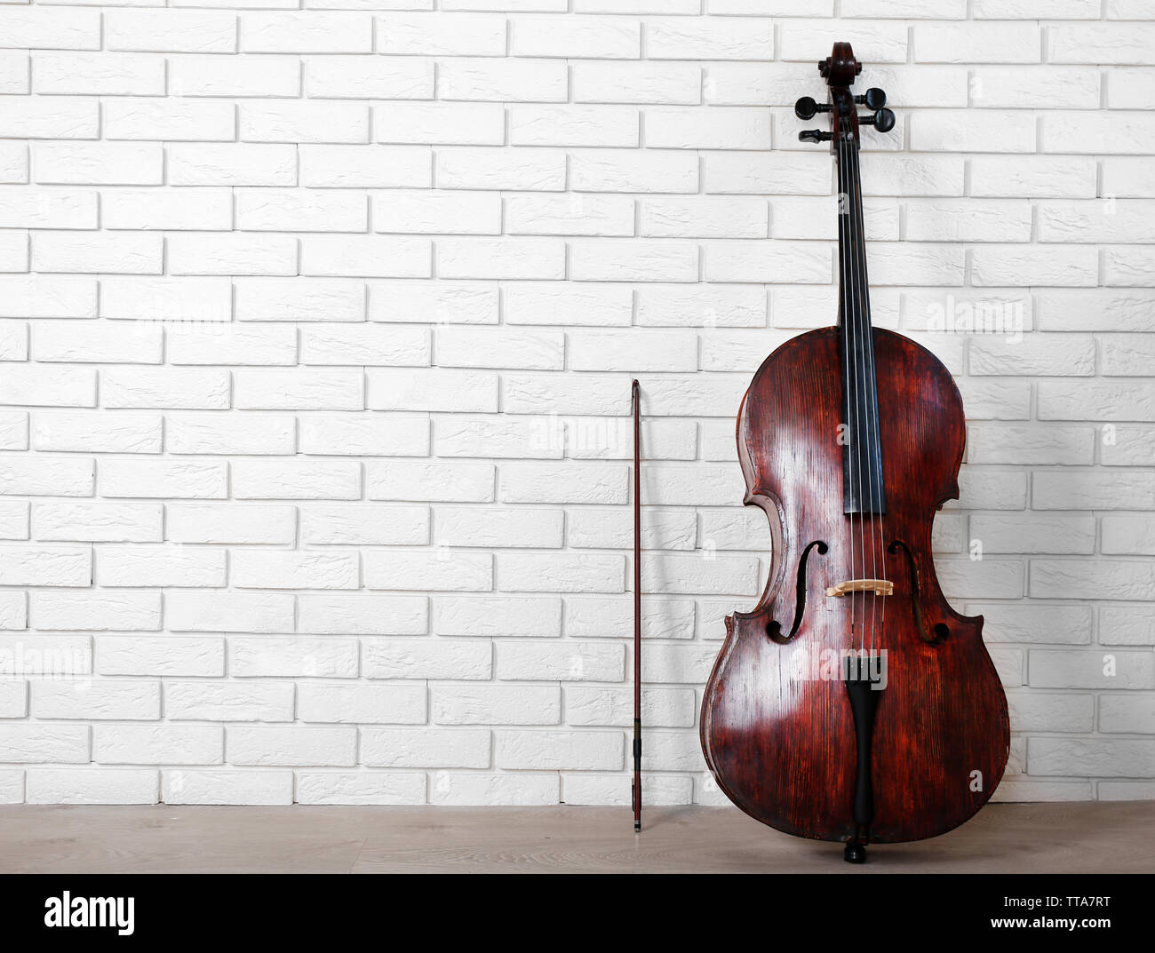 Cello on bricks wall background Stock Photo - Alamy